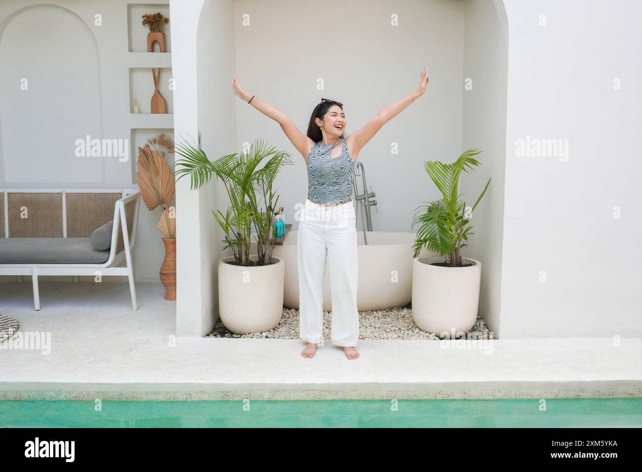 Full body of Asian young woman in pattern top and white pants spreading ...