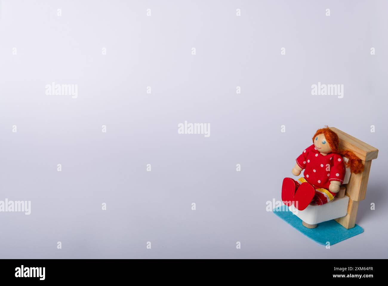 A wooden toy figure of a girl sits on a toilet, all elements crafted ...