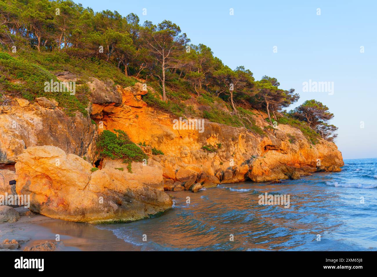 Lush cliffs rise over peaceful waters, creating a picturesque coastal ...