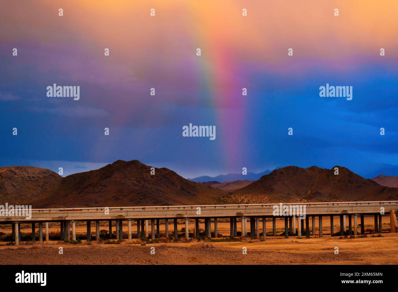 Vivid rainbow, set against dramatic mixed-sky backdrop, arcs over ...