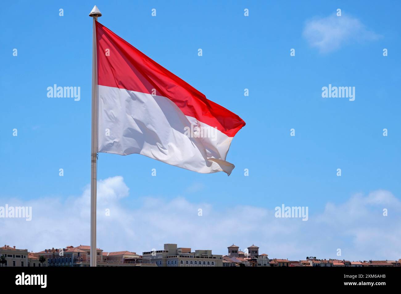 The flag of Monaco waving in the wind in front of a blue sky Stock ...