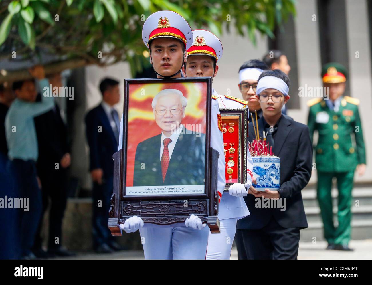 A member of Vietnam's armed forces carries a portrait of the late ...