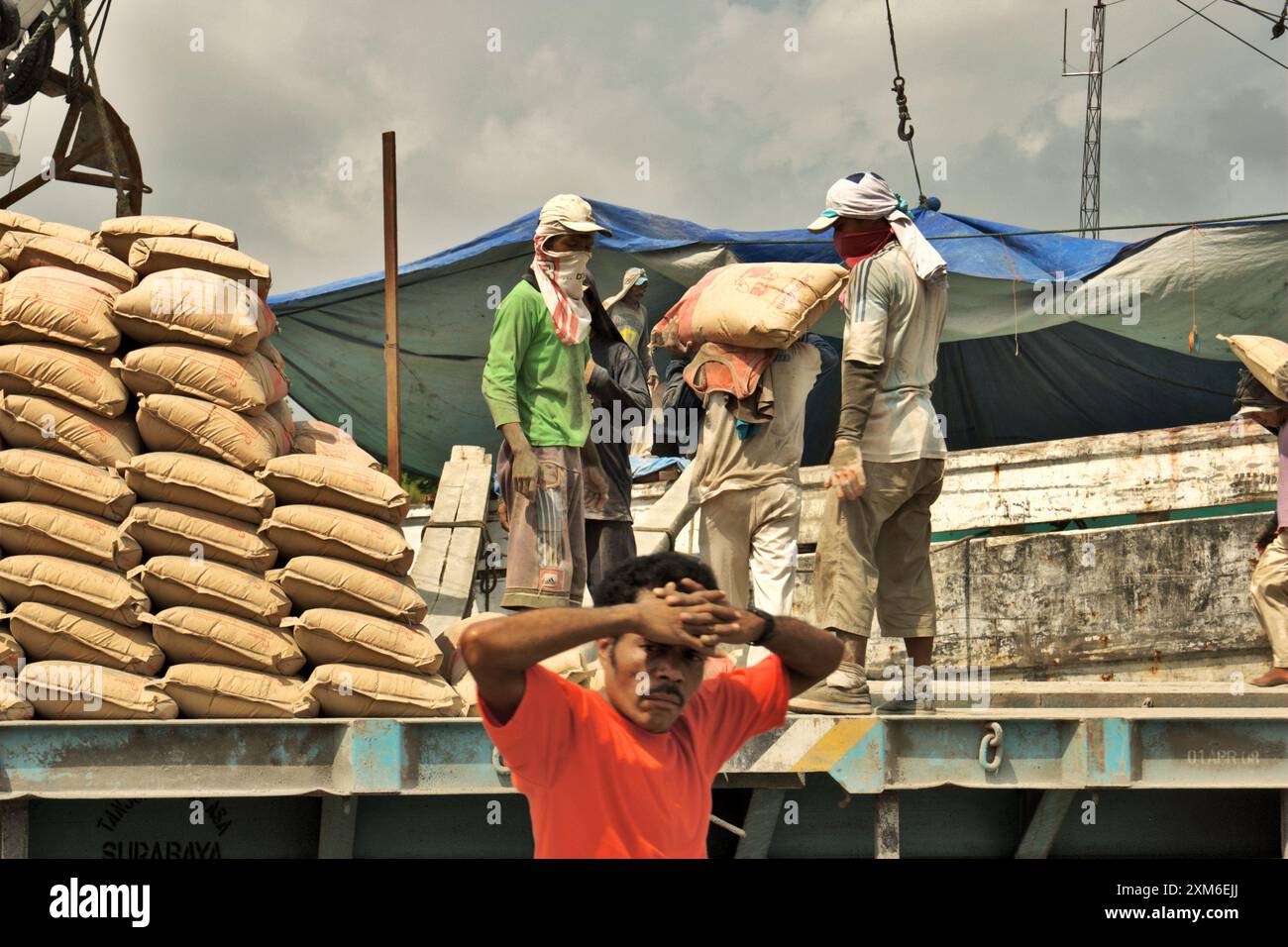 A man walking on harbour platform, in a background of workers ...
