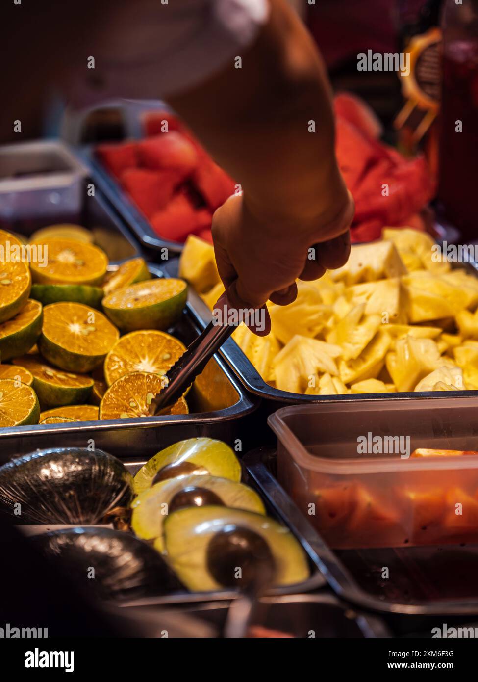 A hand reaches for a piece of fruit from a stall selling fruits Stock ...