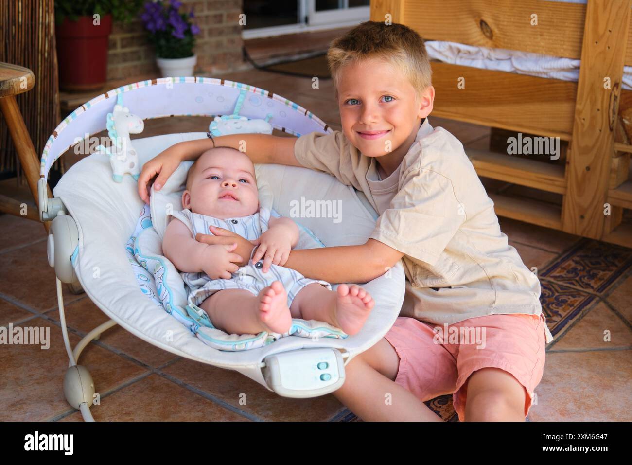Big brother hugging baby brother relaxing in swing Stock Photo - Alamy