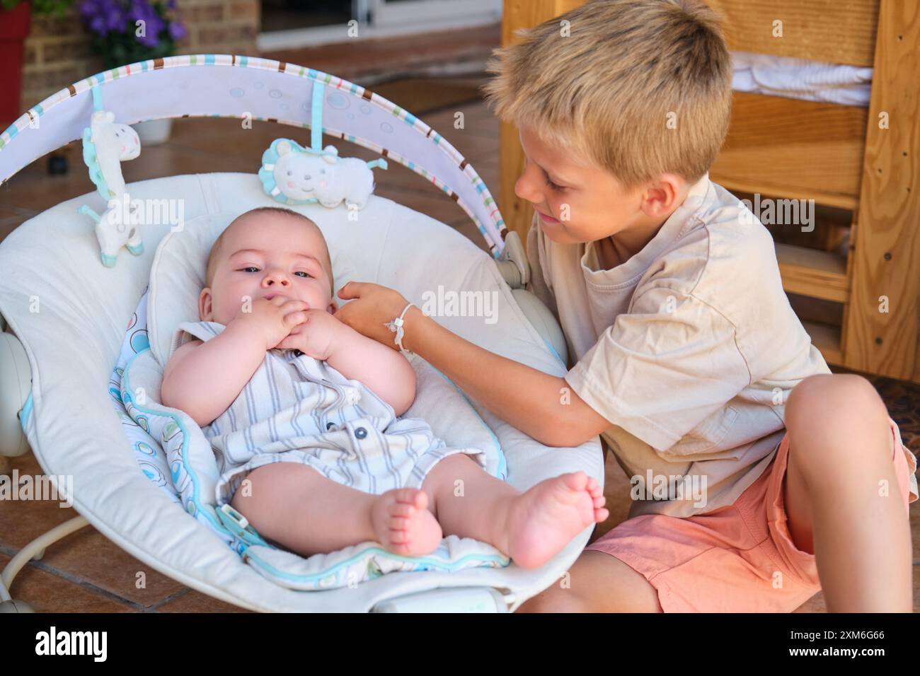 Older brother playing with baby brother relaxing in baby bouncer Stock ...