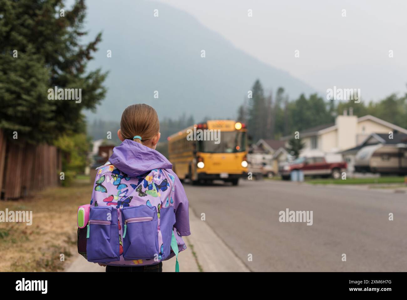 Little girl with backpack waits for bus on first day of school Stock ...