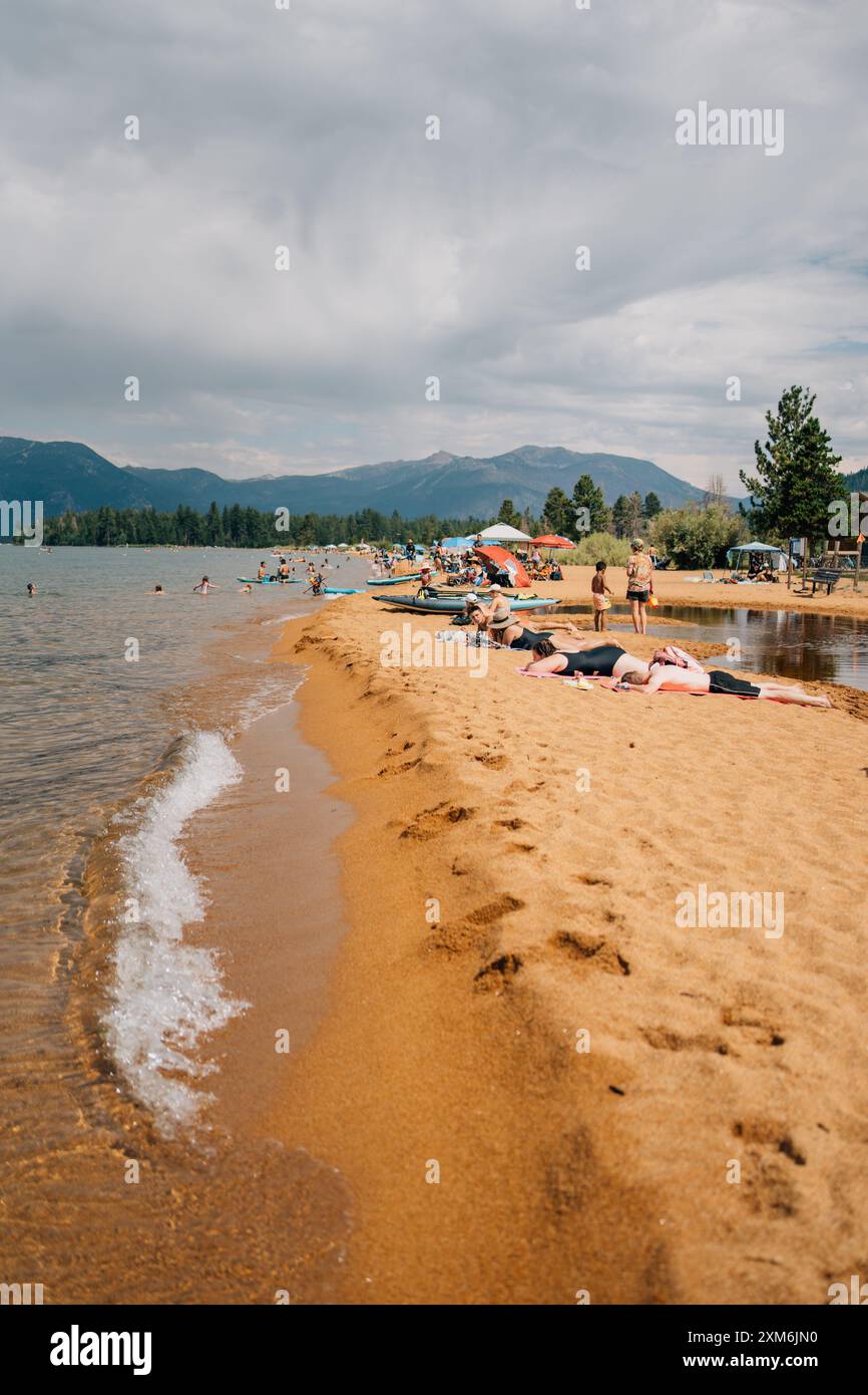 People on the beach of a lake sunbathing and paddle boarding Stock ...
