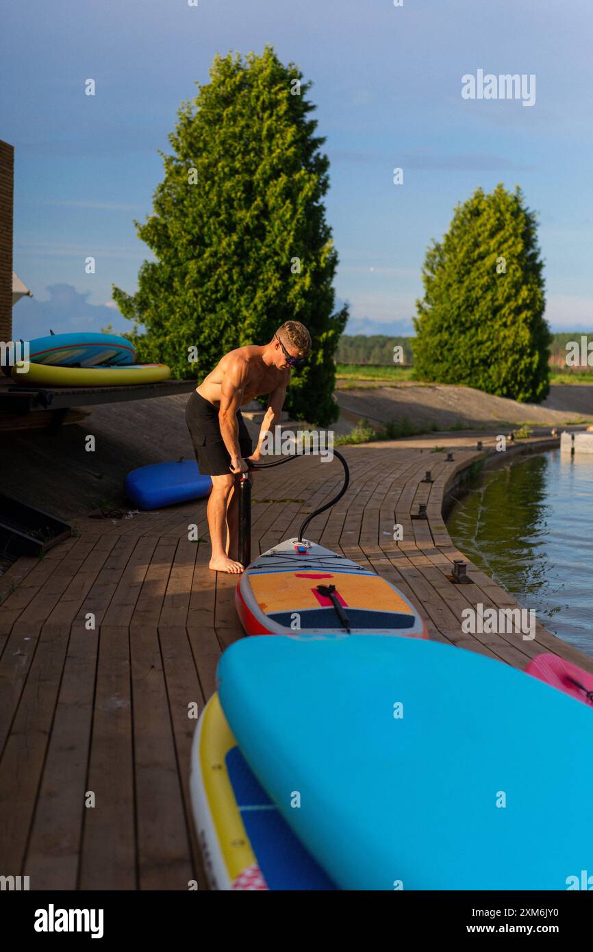 Man pumps up inflatable SUP Stock Photo - Alamy