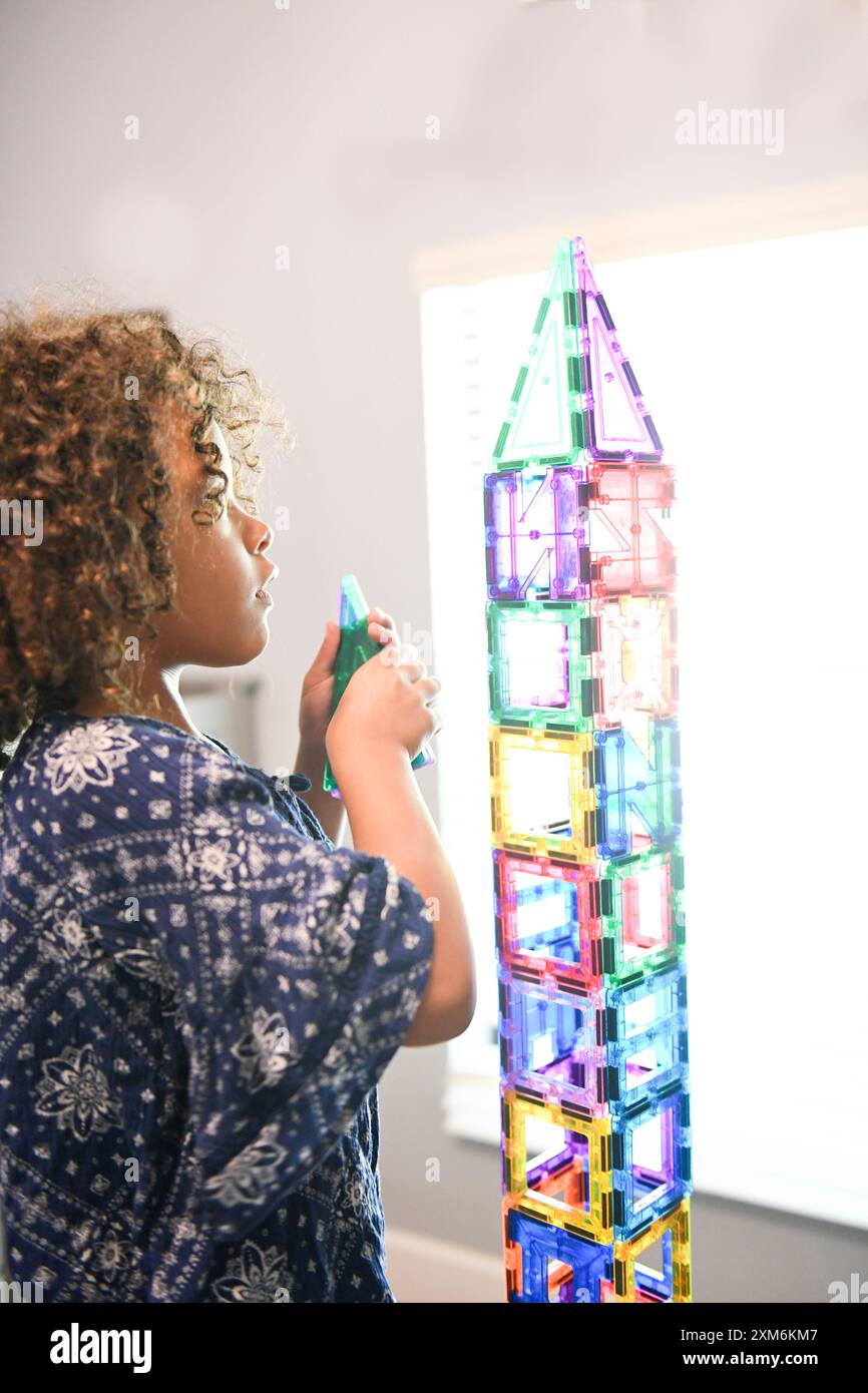 Young girl building a tall, colorful block, magnetic tile tower Stock ...
