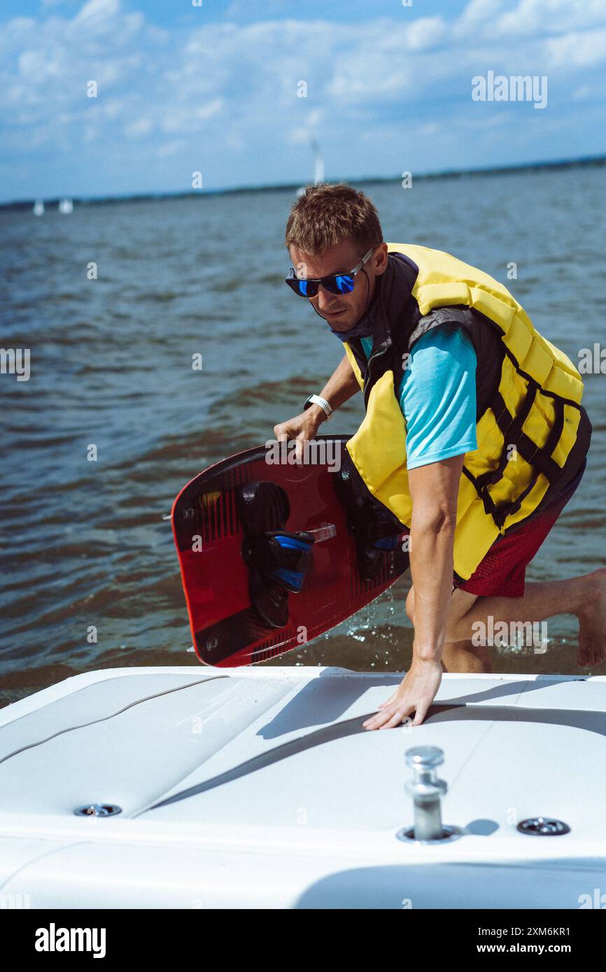 A man loads wakeboard equipment onto a boat Stock Photo - Alamy
