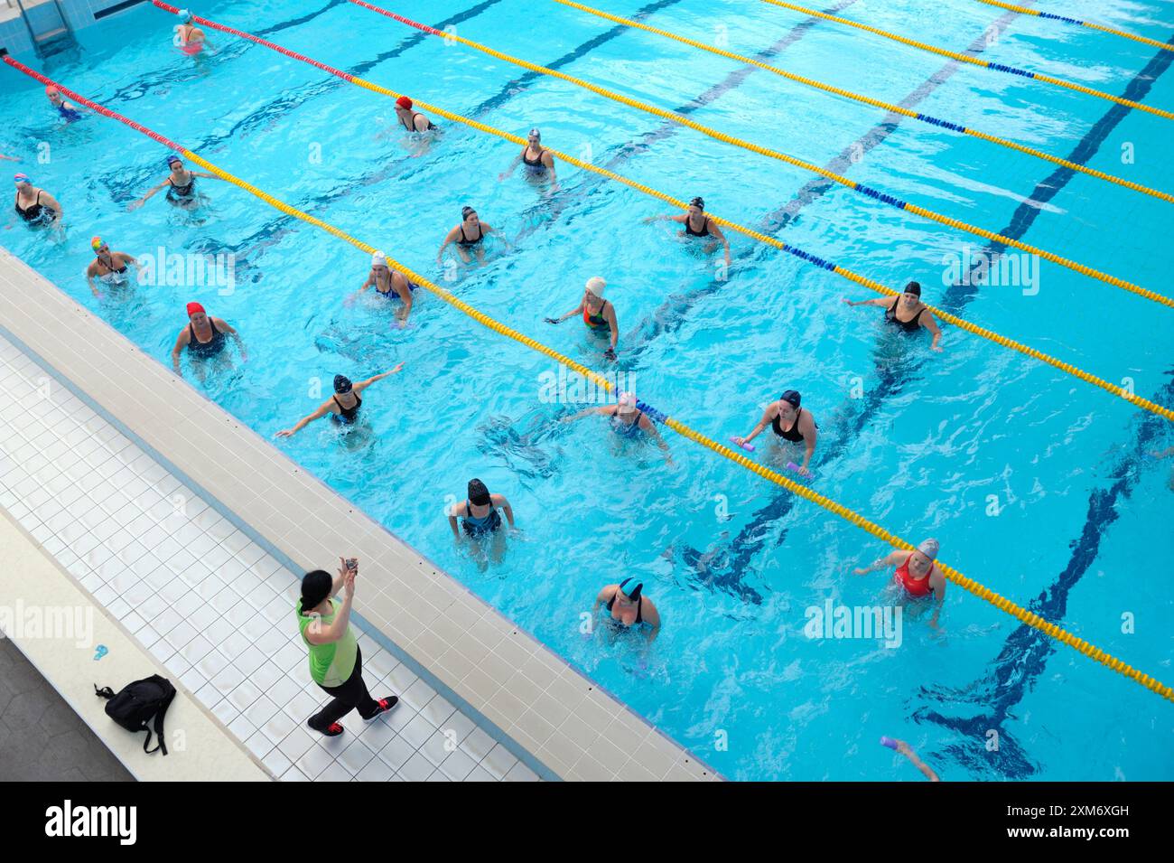Woman trainer teaching group of beginners of swimming in an indoor ...