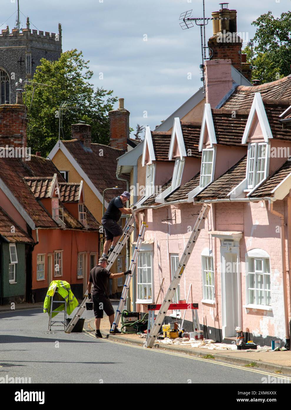 Two workmen up ladders on a pleasant redecorating a cottage in Castle ...