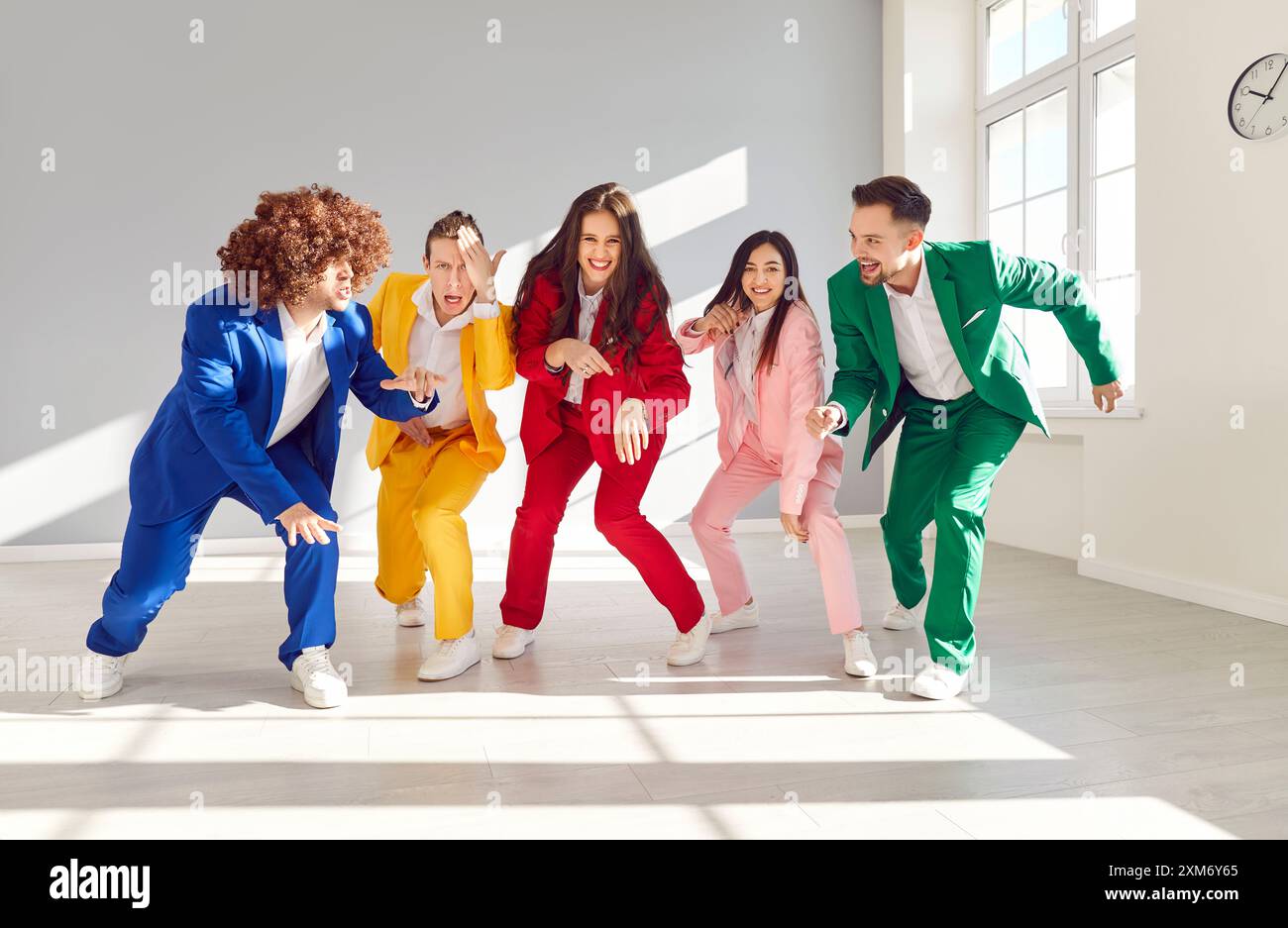 Funny cheerful young people dancers in bright suits dancing together ...