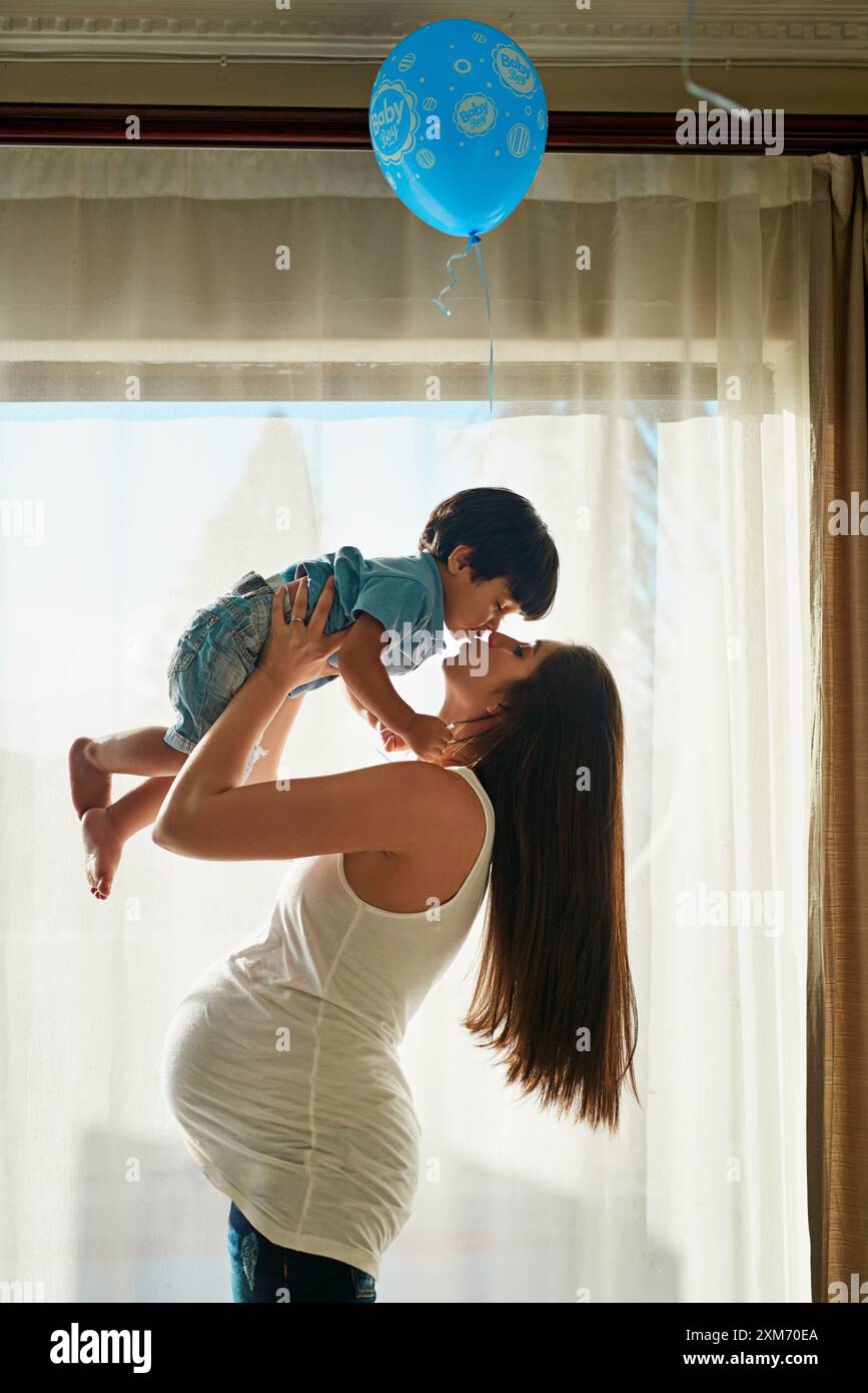 Pregnancy, balloon and mom with child kiss for bonding, loving ...