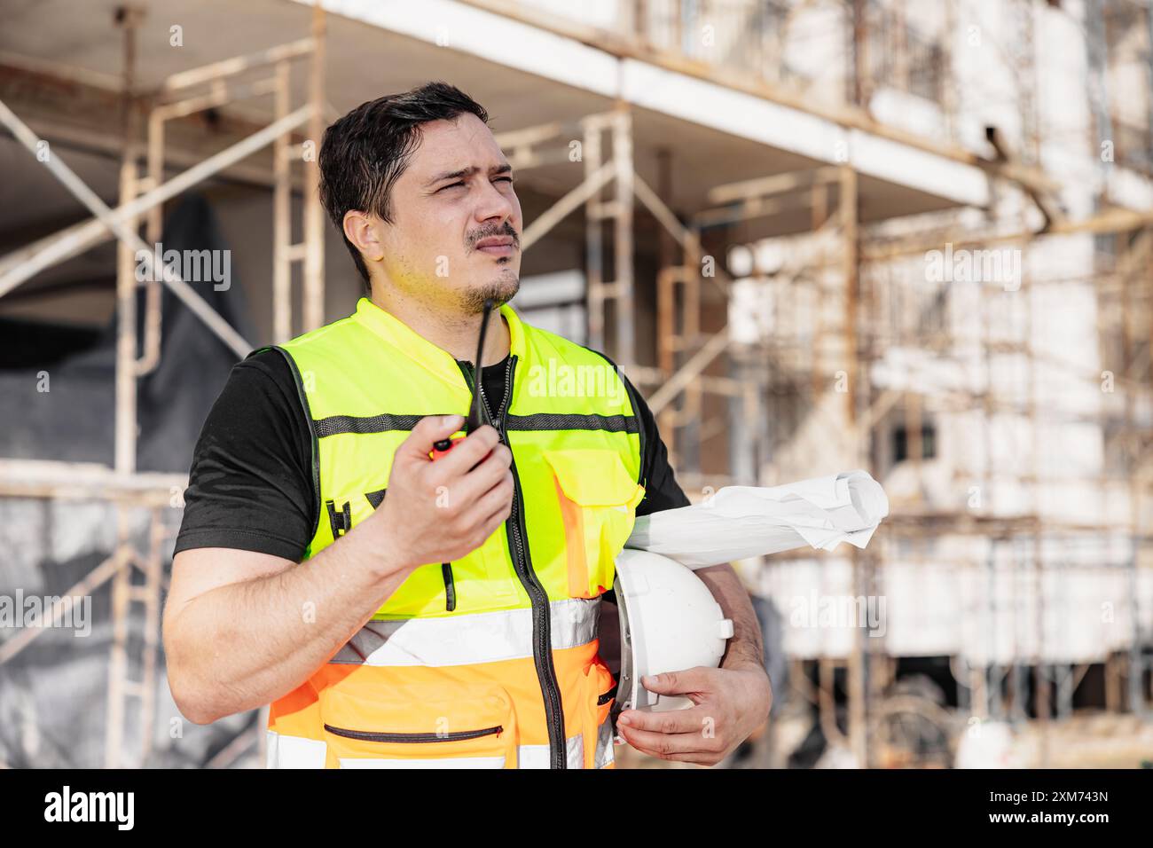 Construction engineer in a reflective vest using a walkie talkie while ...
