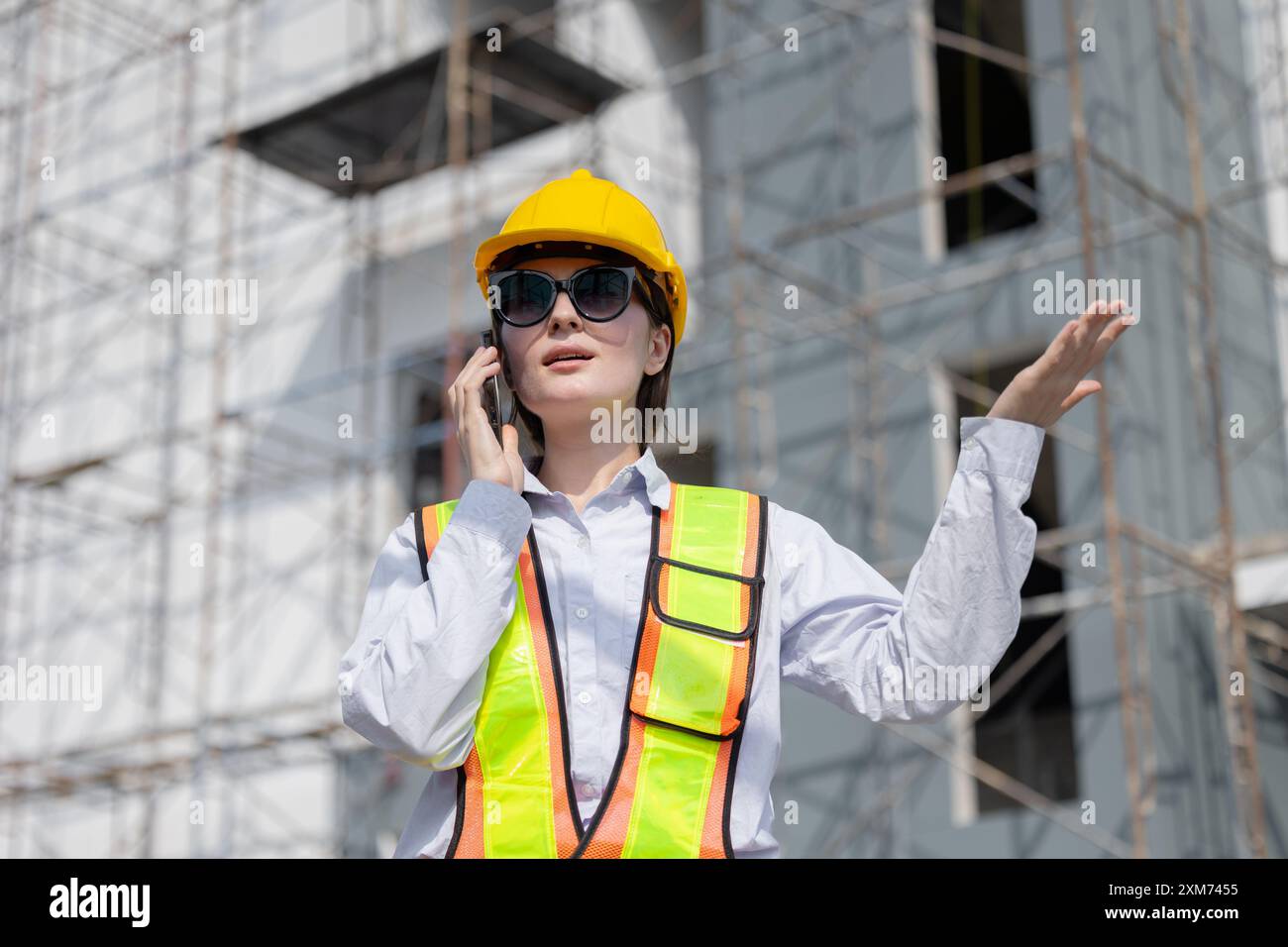 A construction worker wearing a safety helmet and vest speaks on the ...