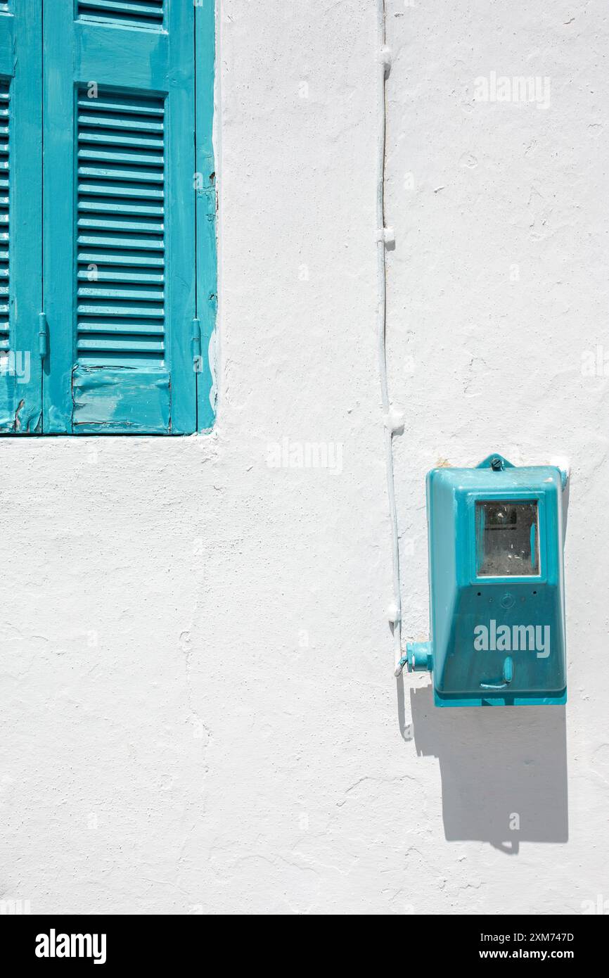 A blue window with shutters and an electric meter are attached to a ...