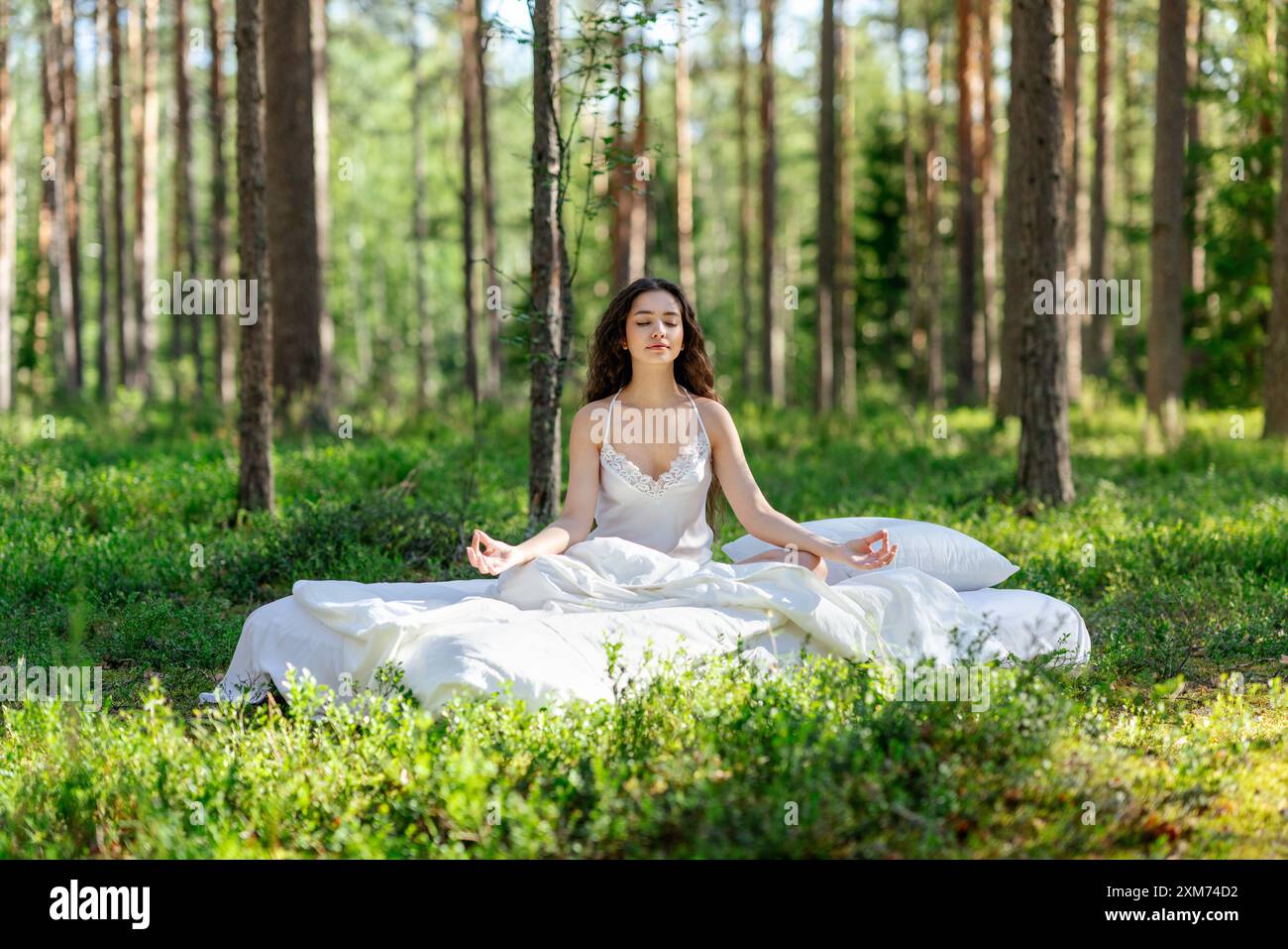 Young woman is resting on a mattress in the lotus position, in summer ...