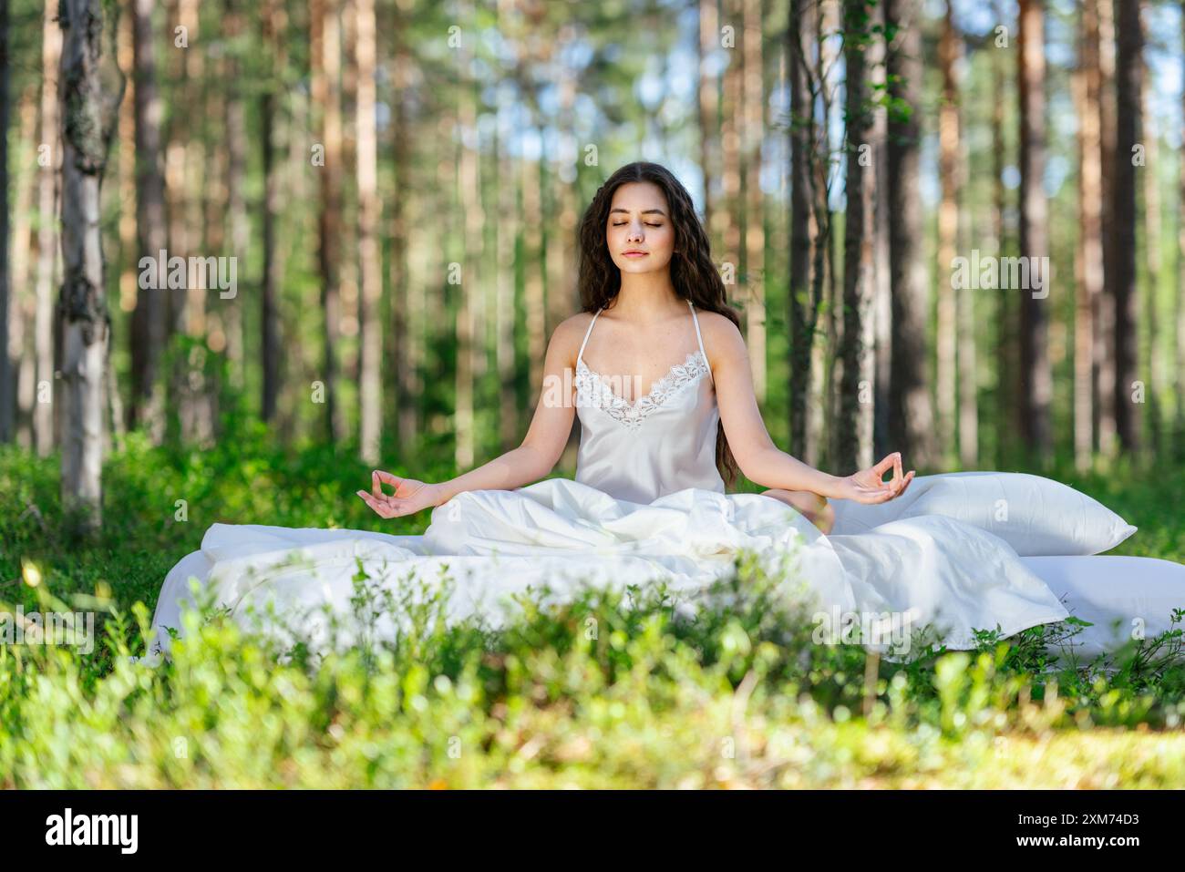 Young woman is resting on a mattress in the lotus position, in summer ...