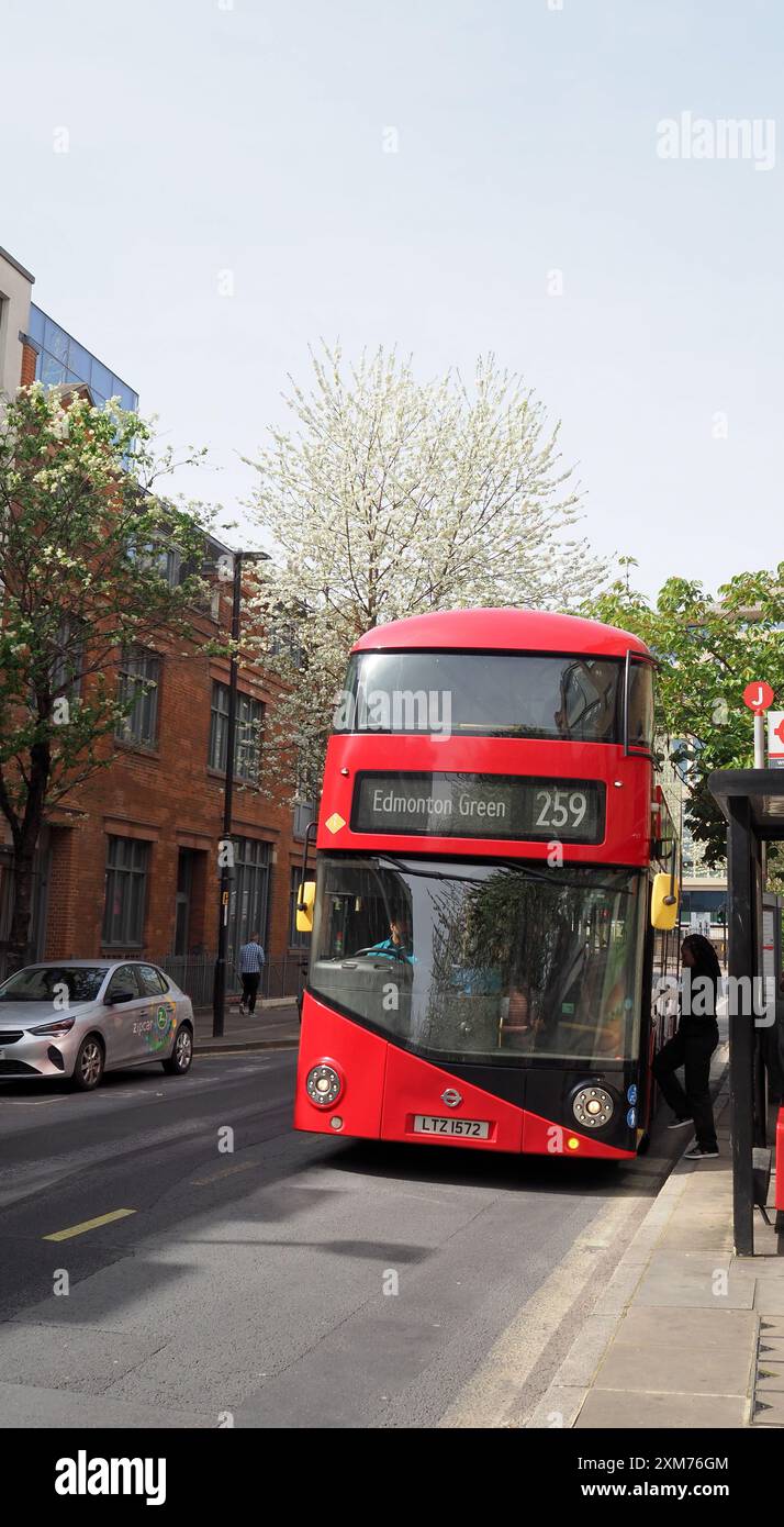 An iconic red London double-decker bus picking up passengers at a bus ...