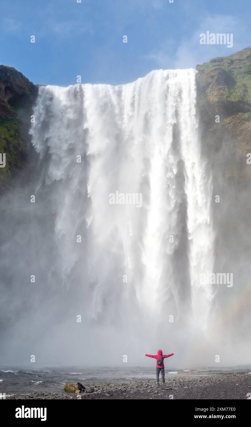 Skogafoss waterfall with an unidentified woman under the waterfall and ...