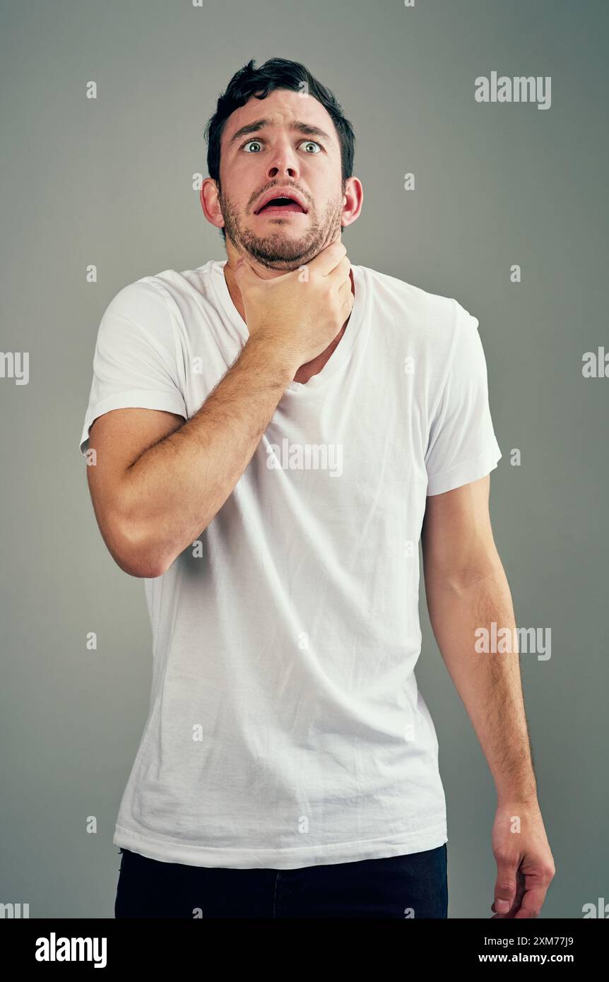 Neck, choke or scared man with stress in studio on grey background with fear, trouble or anxiety ...