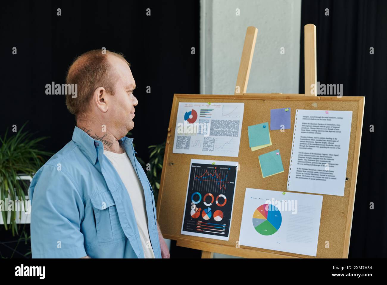 A man with inclusivity stands by a corkboard with charts and papers ...