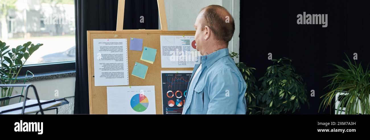 A man with inclusivity looks at a bulletin board covered in papers and ...