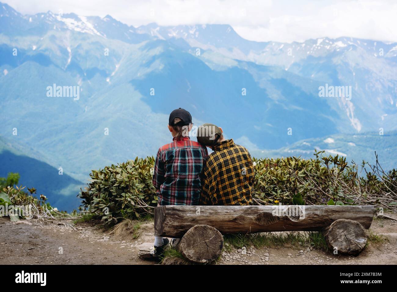 children sitting on log bench observing beautiful mountains view Stock ...