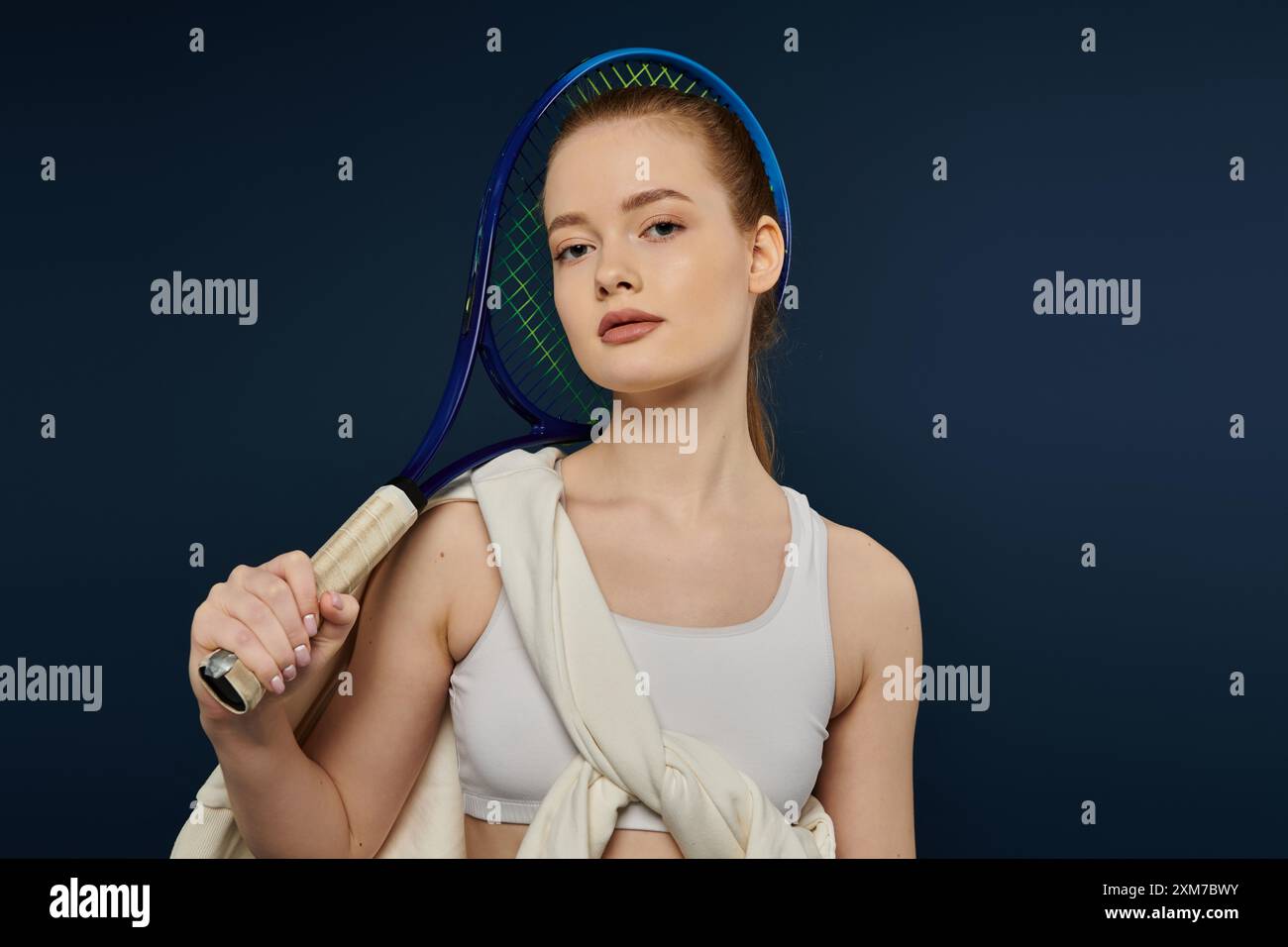 Young woman poses with tennis racket, wearing white sports bra and ...
