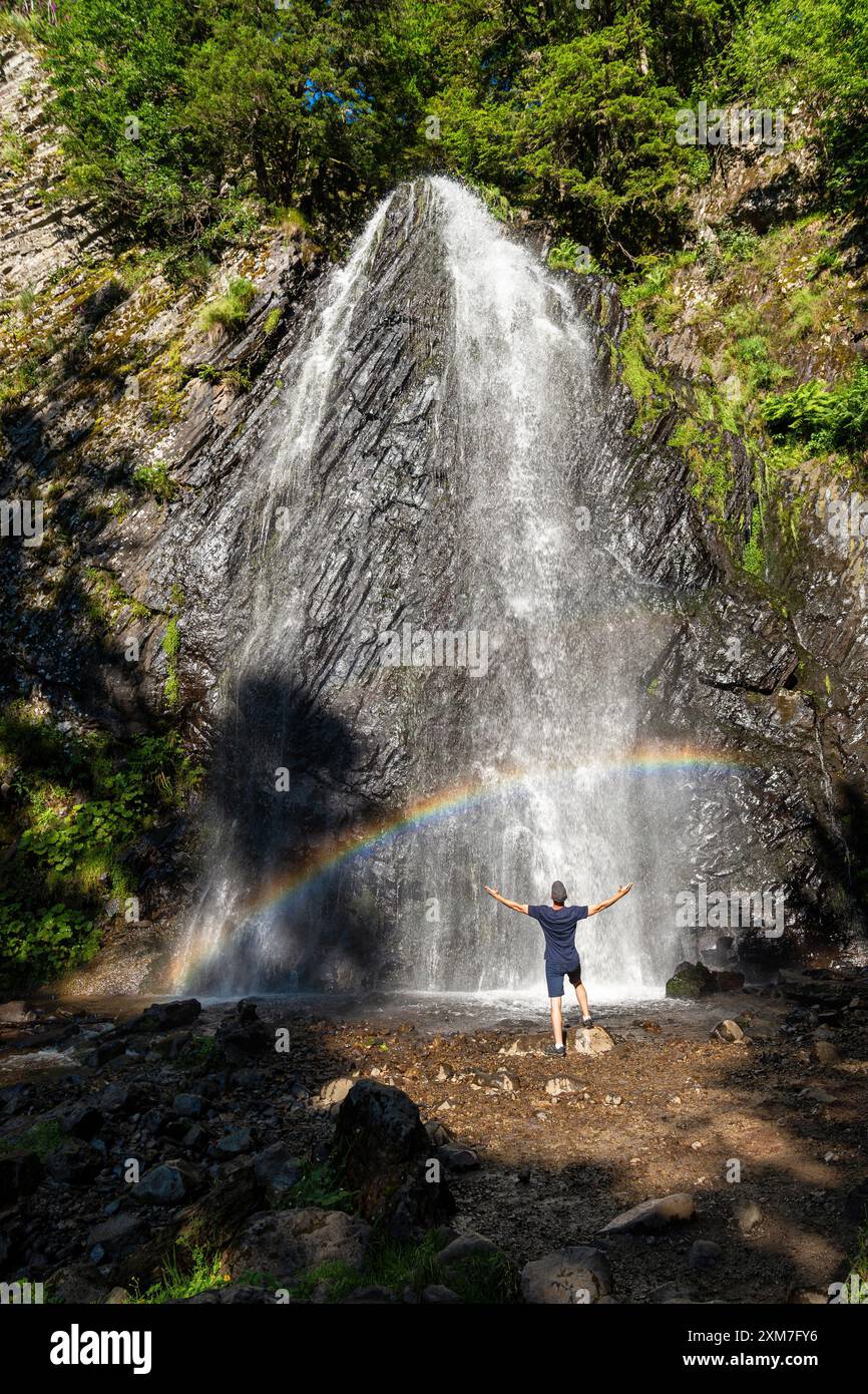 Rear view of young man standing with arms raised in front of the ...