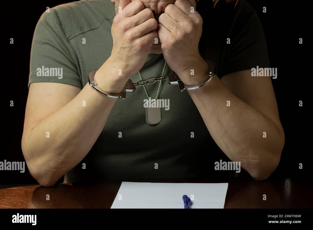 A handcuffed military man signs a document on white paper ...