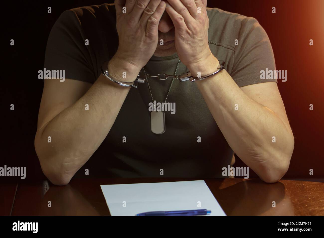 A handcuffed military man signs a document on white paper ...