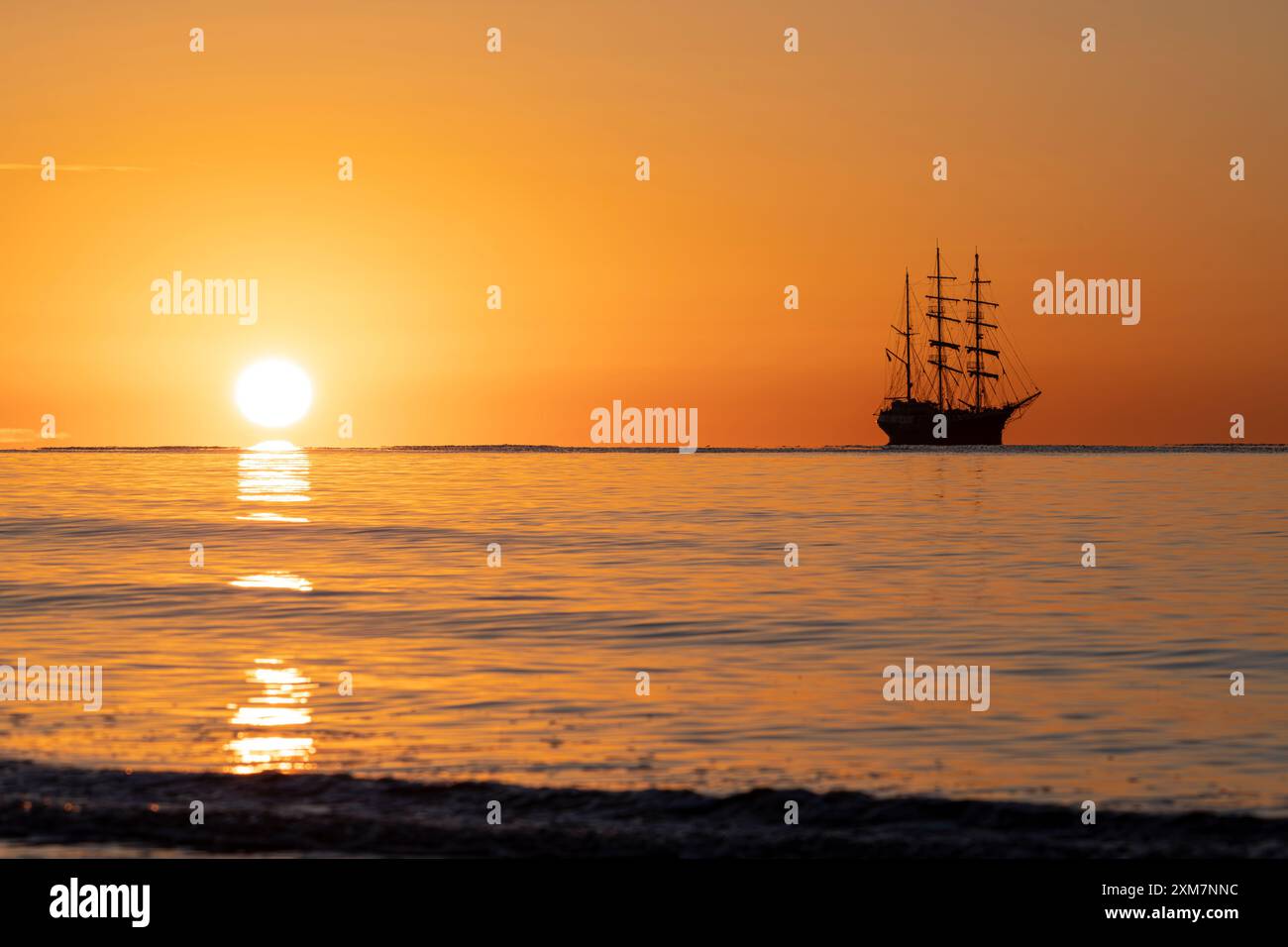 Sailing Ship Pirate type on horizon with very low sun rising setting ...