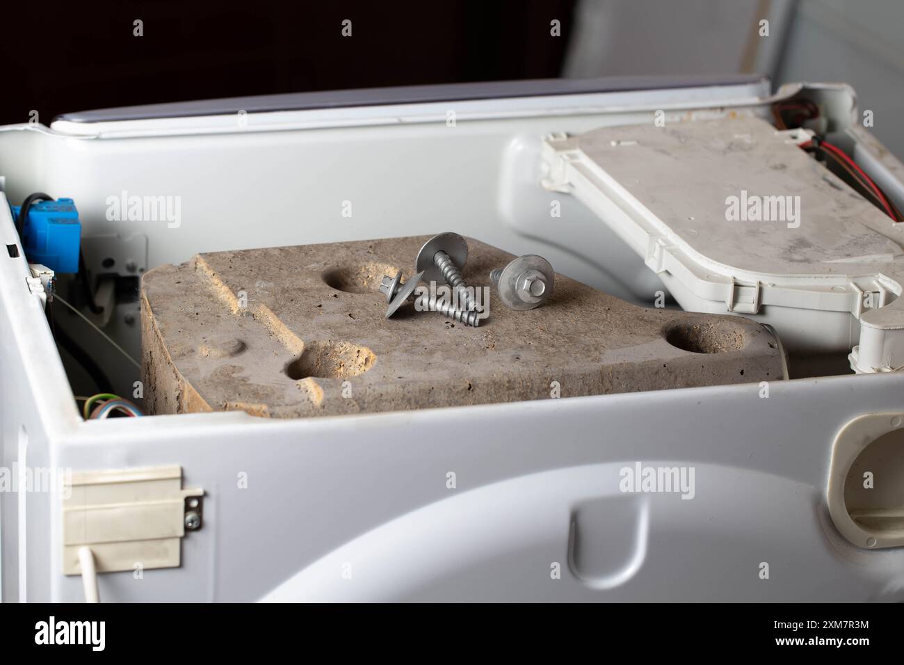 Bolts and tools lie on the counterweight of the washing machine ...