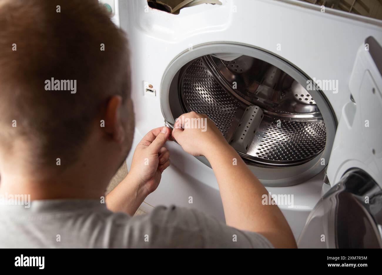 The technician changes the rubber seal of the hatch in the washing ...