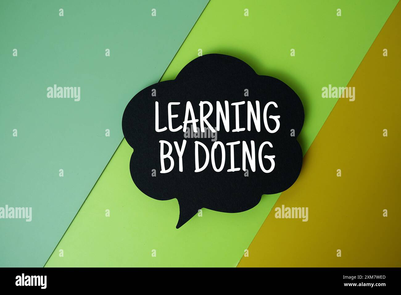 Learning By Doing text on speech bubble top view on green and yellow ...