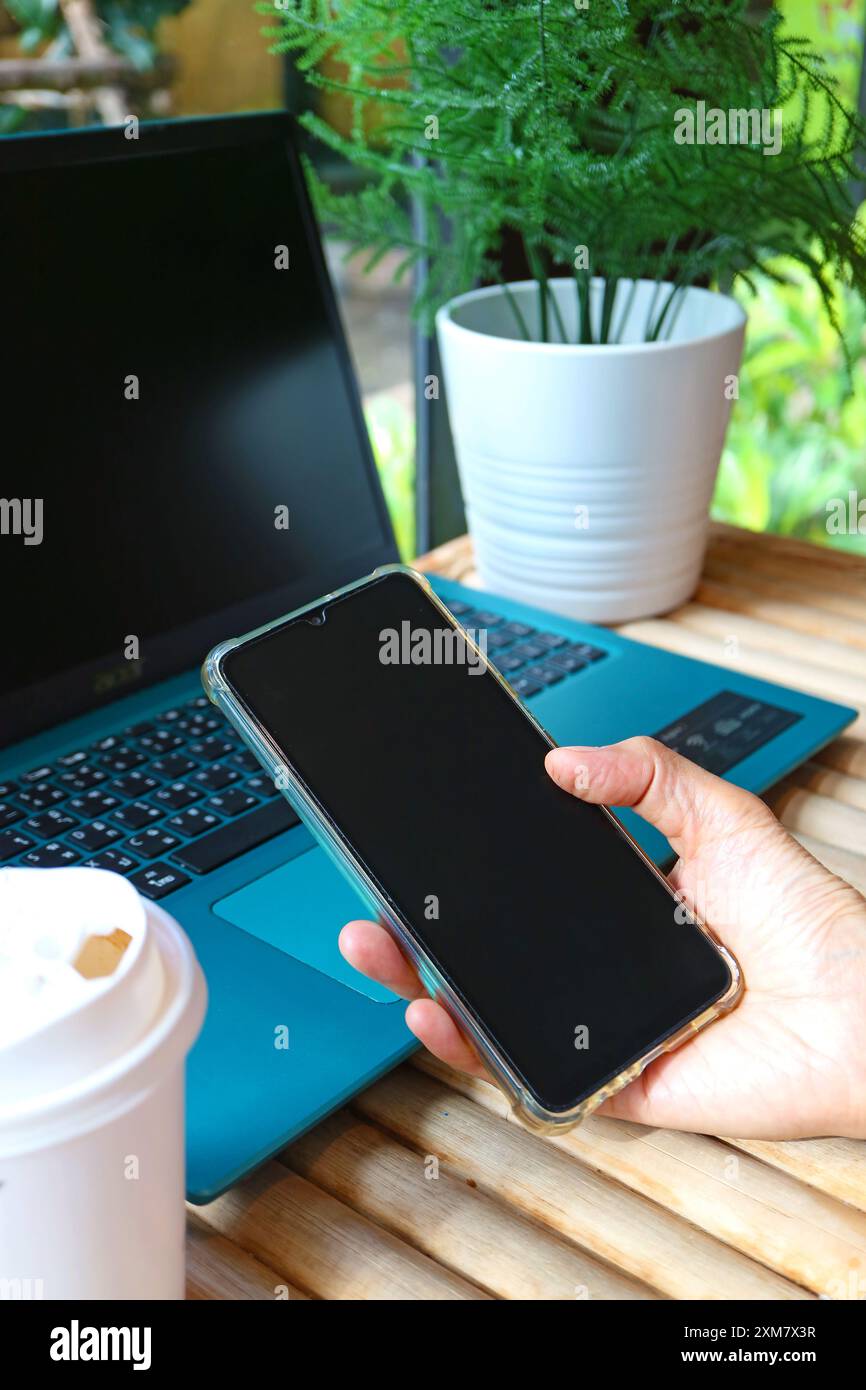 Smartphone in Hand with Laptop in the Backdrop Stock Photo - Alamy