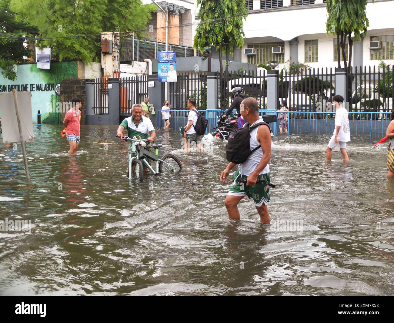 People wade through a flooded street. Typhoon Carina (International ...