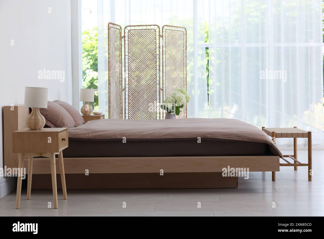 Folding screen, comfortable bed, ottoman and bedside tables in room ...