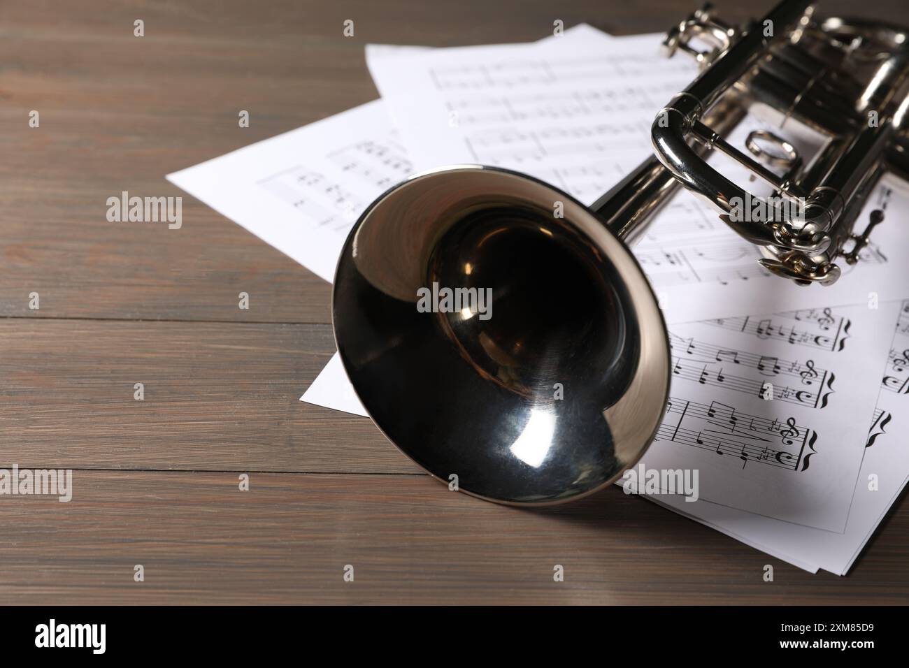 Trumpet and music sheet papers with notes on wooden table, closeup ...