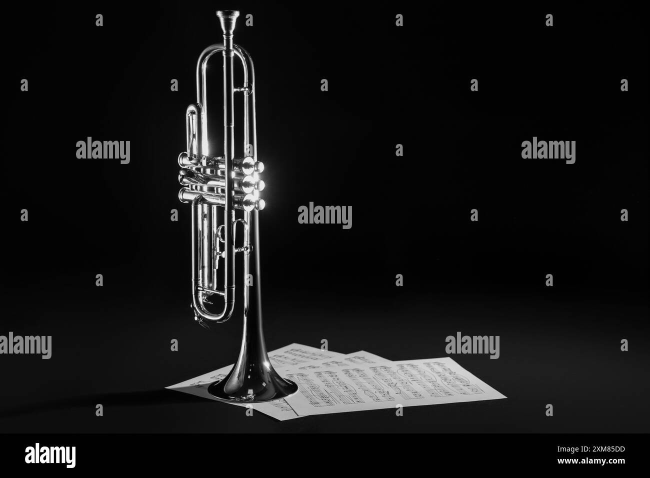 Shiny trumpet and music sheets on dark background, space for text. Wind ...