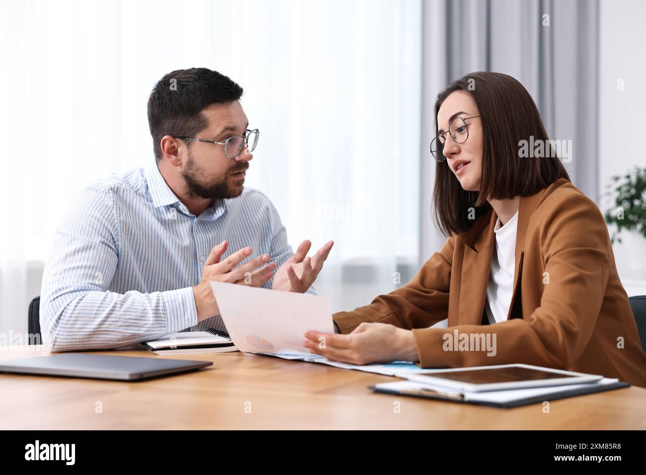 Consultant working with client at table in office Stock Photo - Alamy