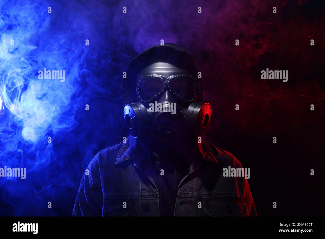 Man wearing gas mask in color lights and smoke on black background ...