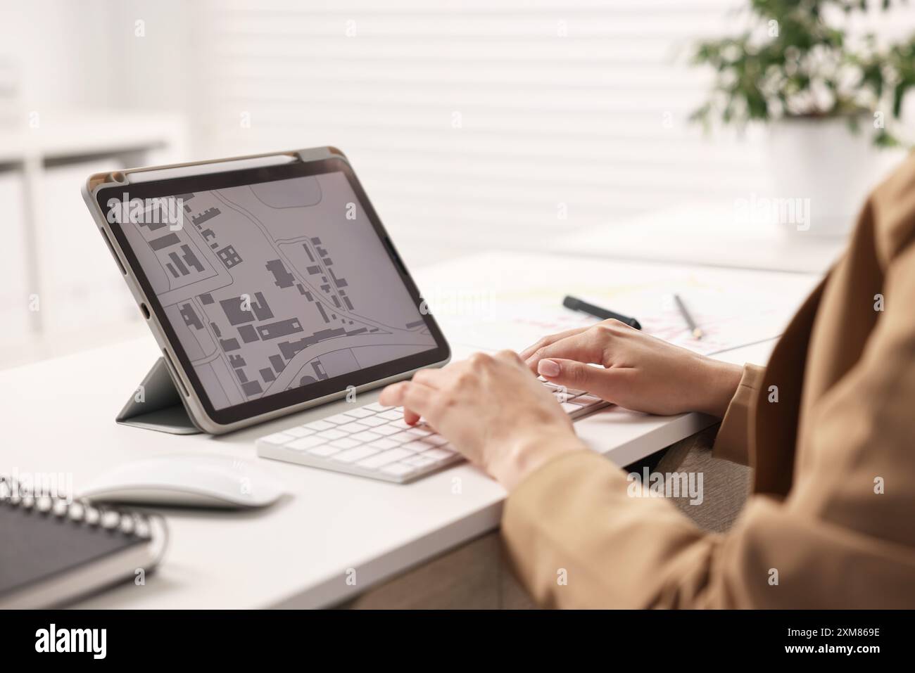 Cartographer working with cadastral map on tablet at white table in ...