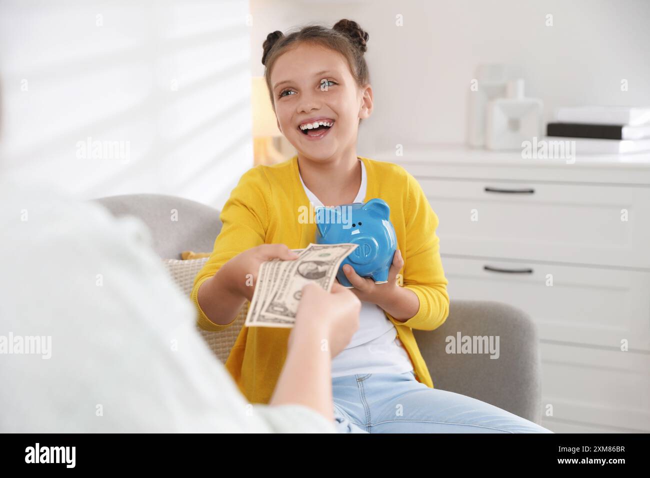Mother giving pocket money to her daughter at home Stock Photo - Alamy