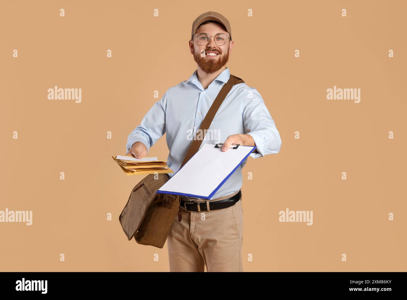 Happy young postman with leather bag delivering letters on brown ...