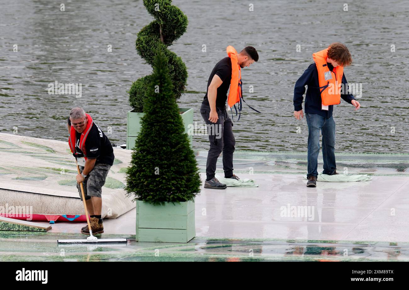 Maintenance workers sweep water off a skateboard ramp installed on a ...