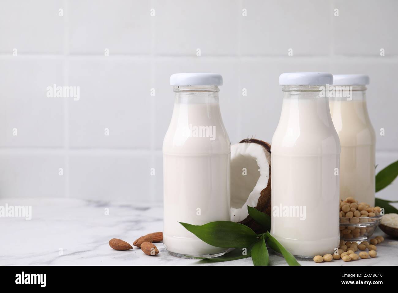 Different types of vegan milk in bottles with ingredients and green ...